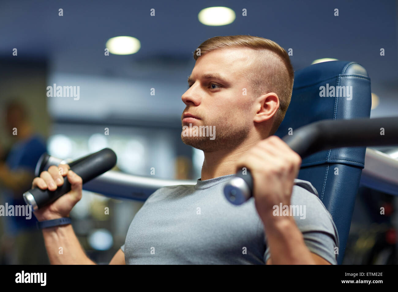 man exercising and flexing muscles on gym machine Stock Photo - Alamy