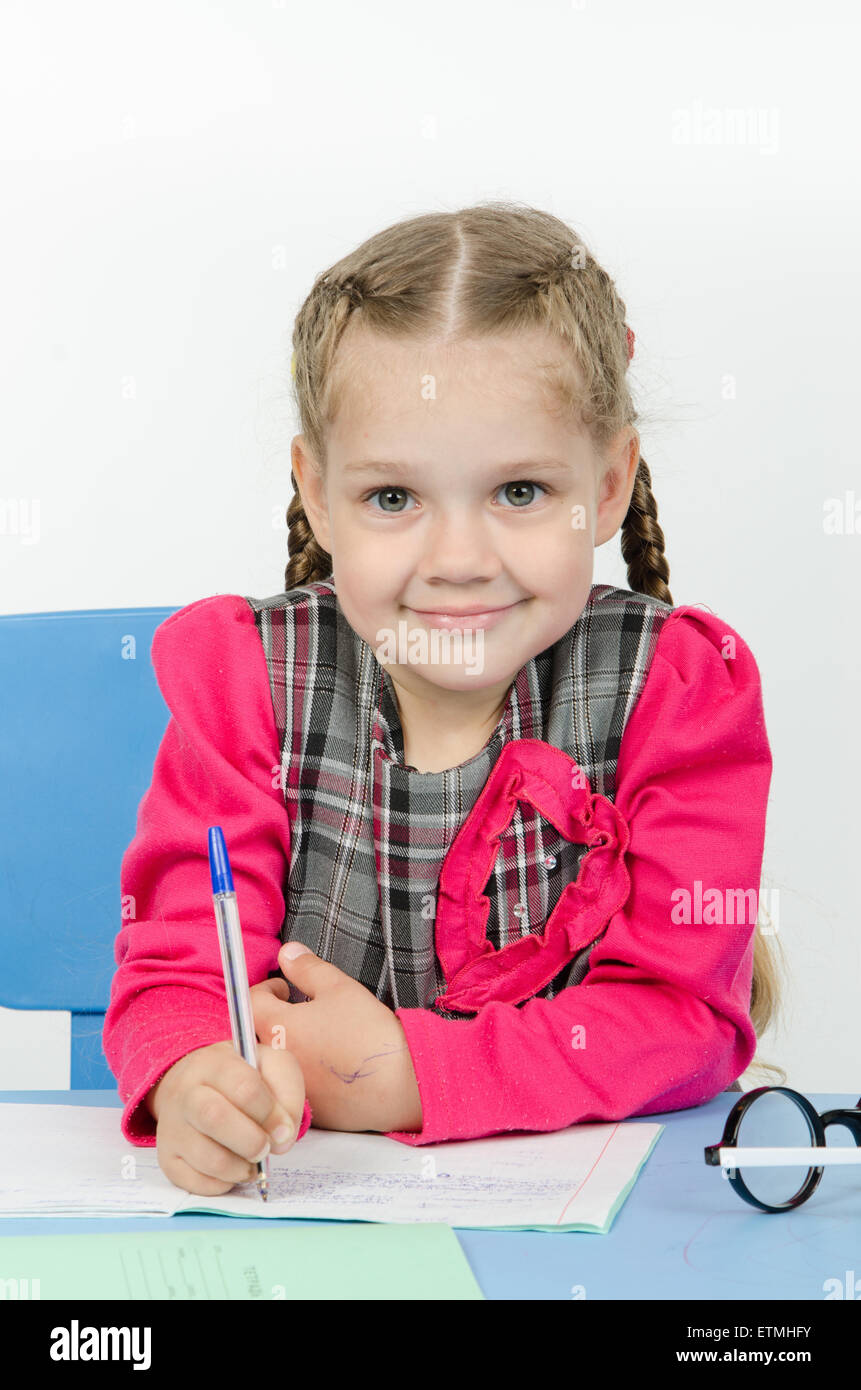 Girl sits at a table on which lay a notebook Stock Photo - Alamy
