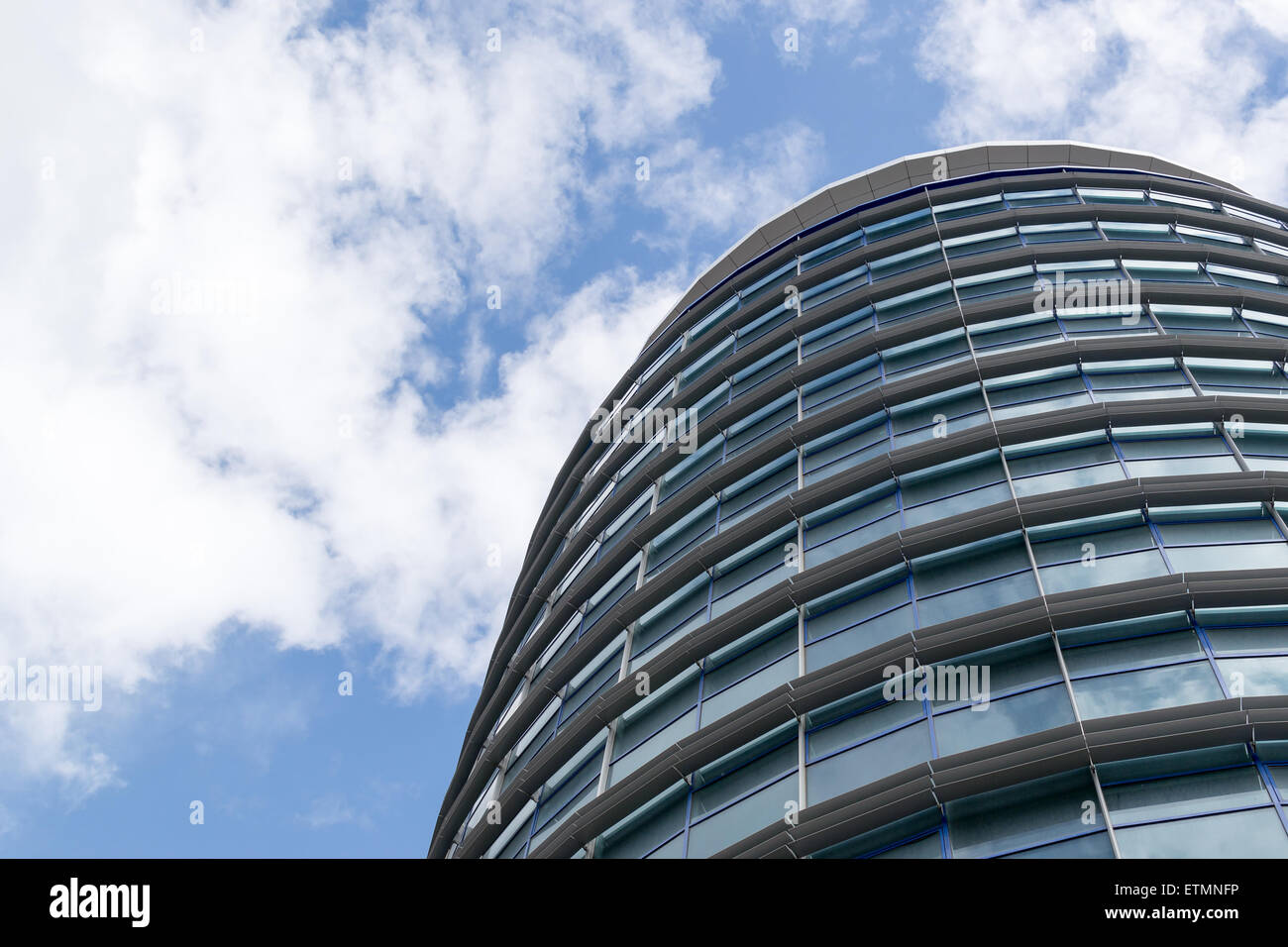 Glass windowed modern business building against a blue sky and clouds ...