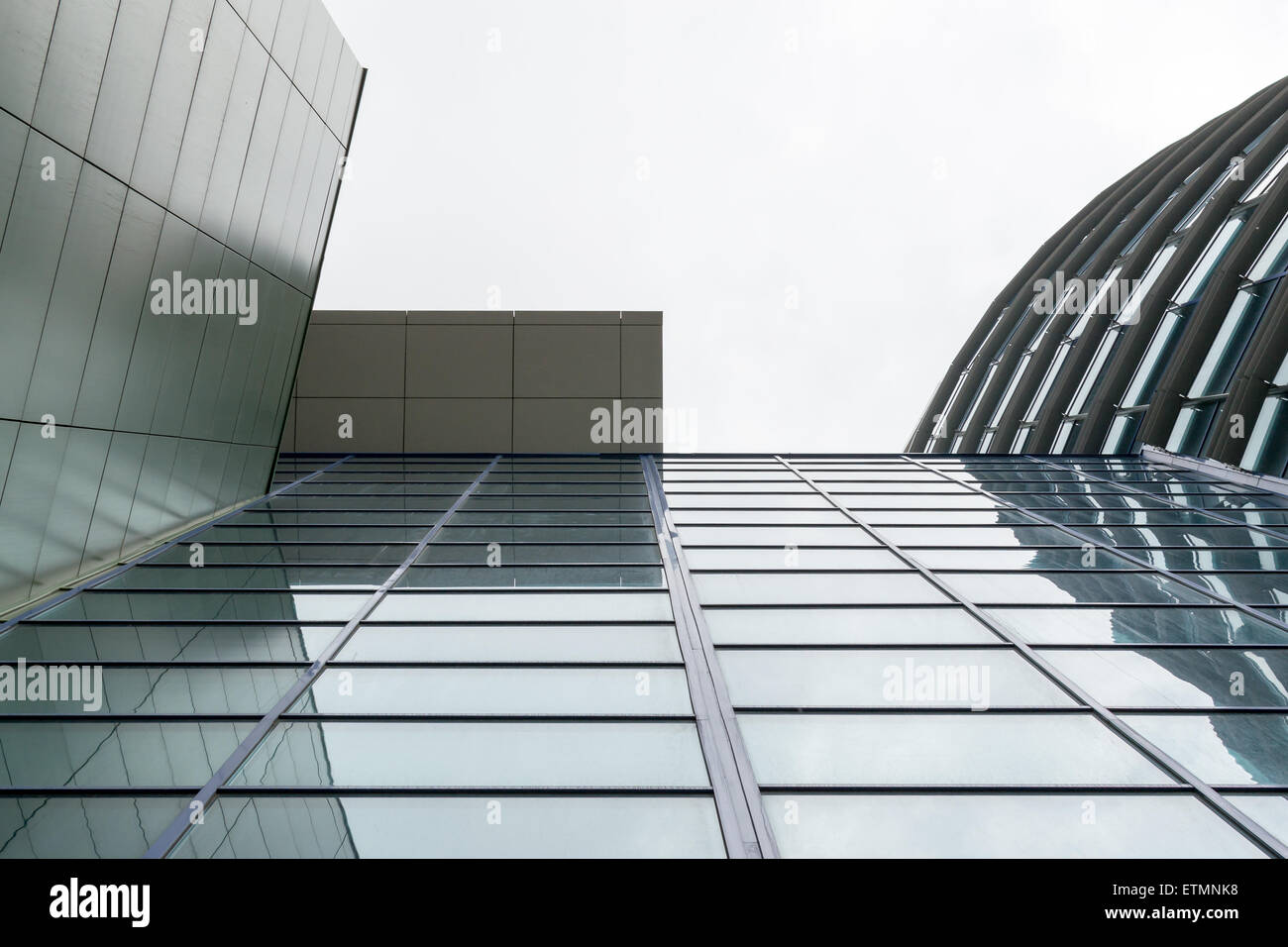 Looking up at a modern style building with angles against white sky ...