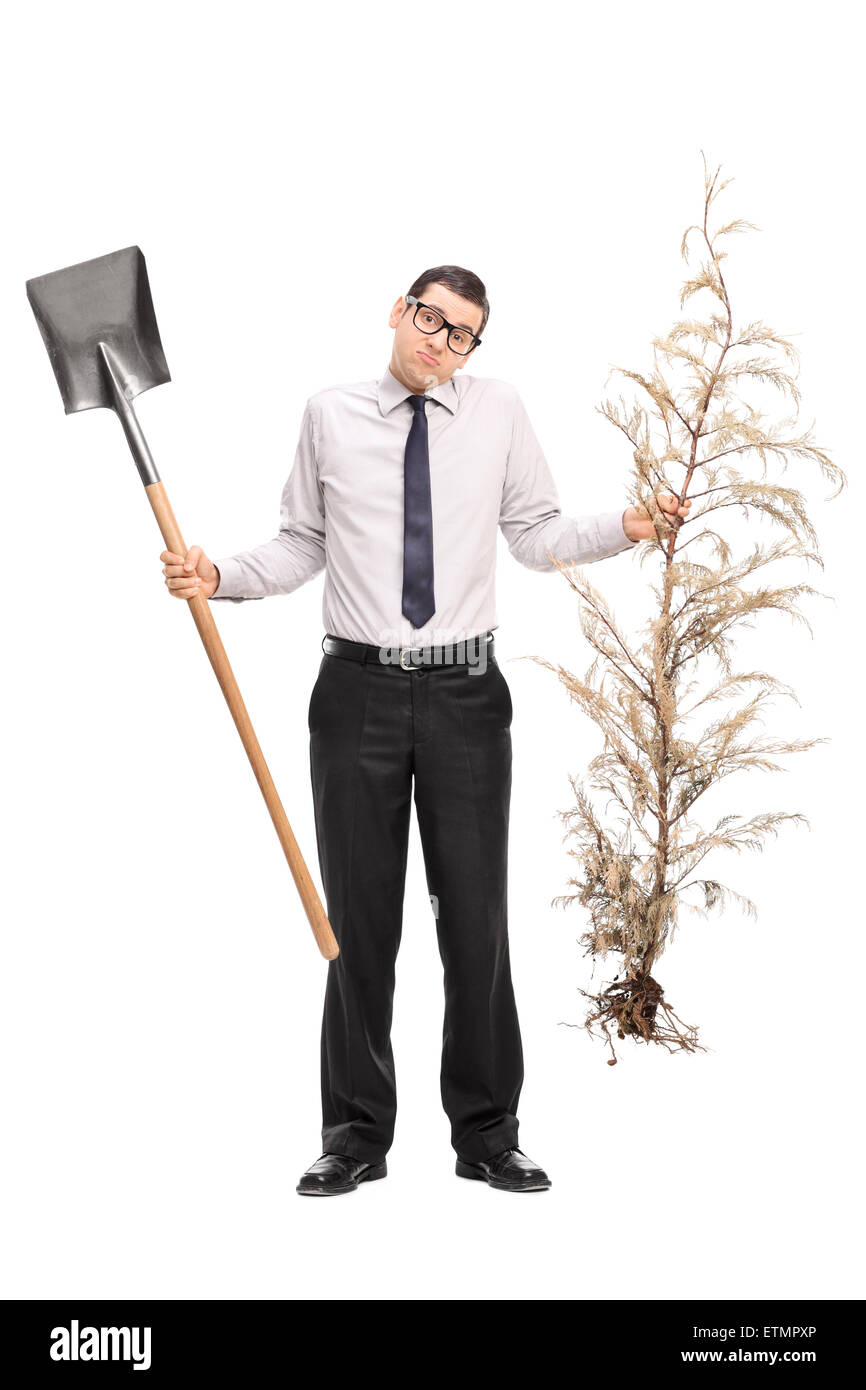 Full length portrait of a confused young guy holding a shovel and a ...