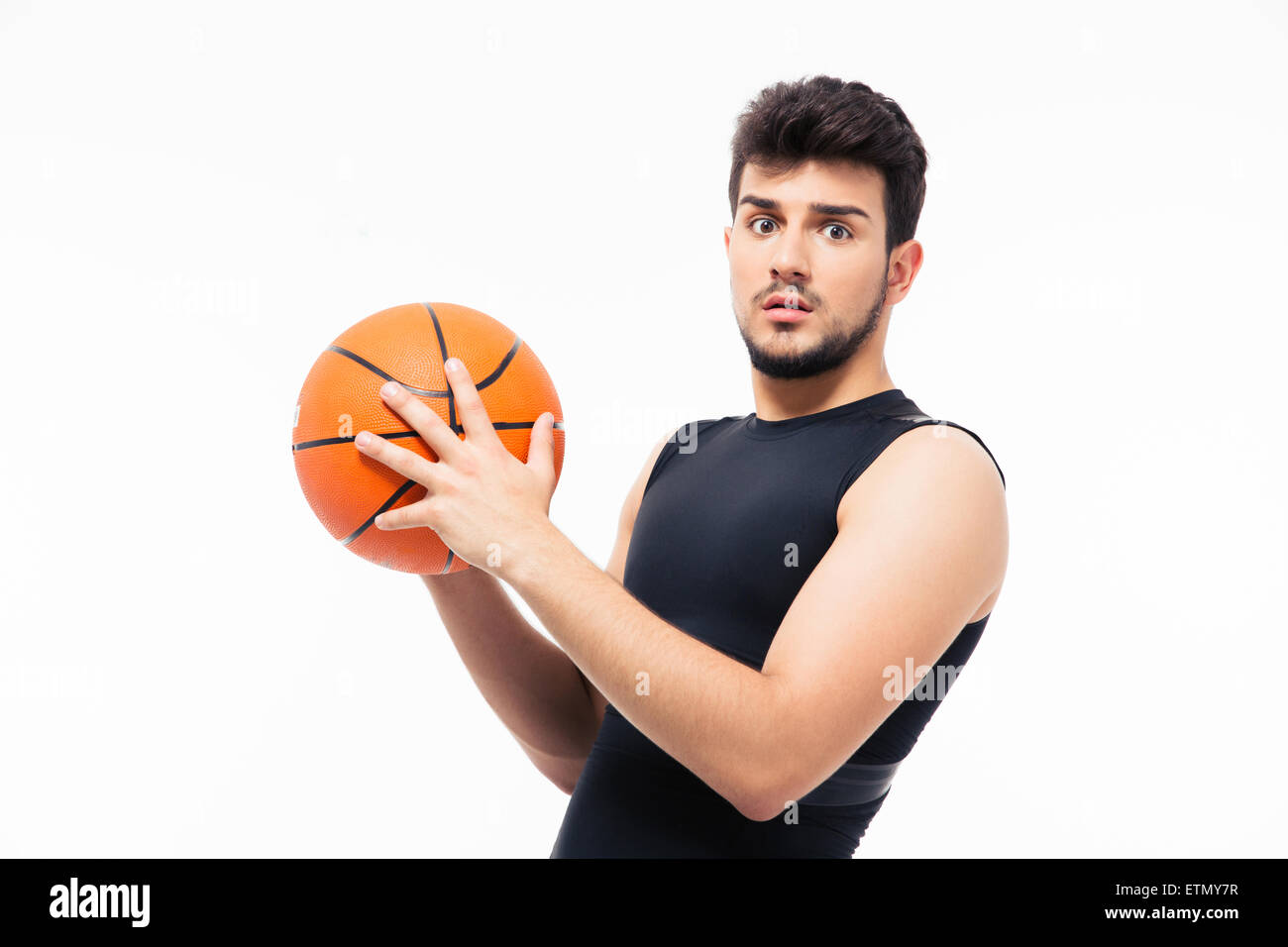 Surprised sports man holding basketball isolated on a white background ...
