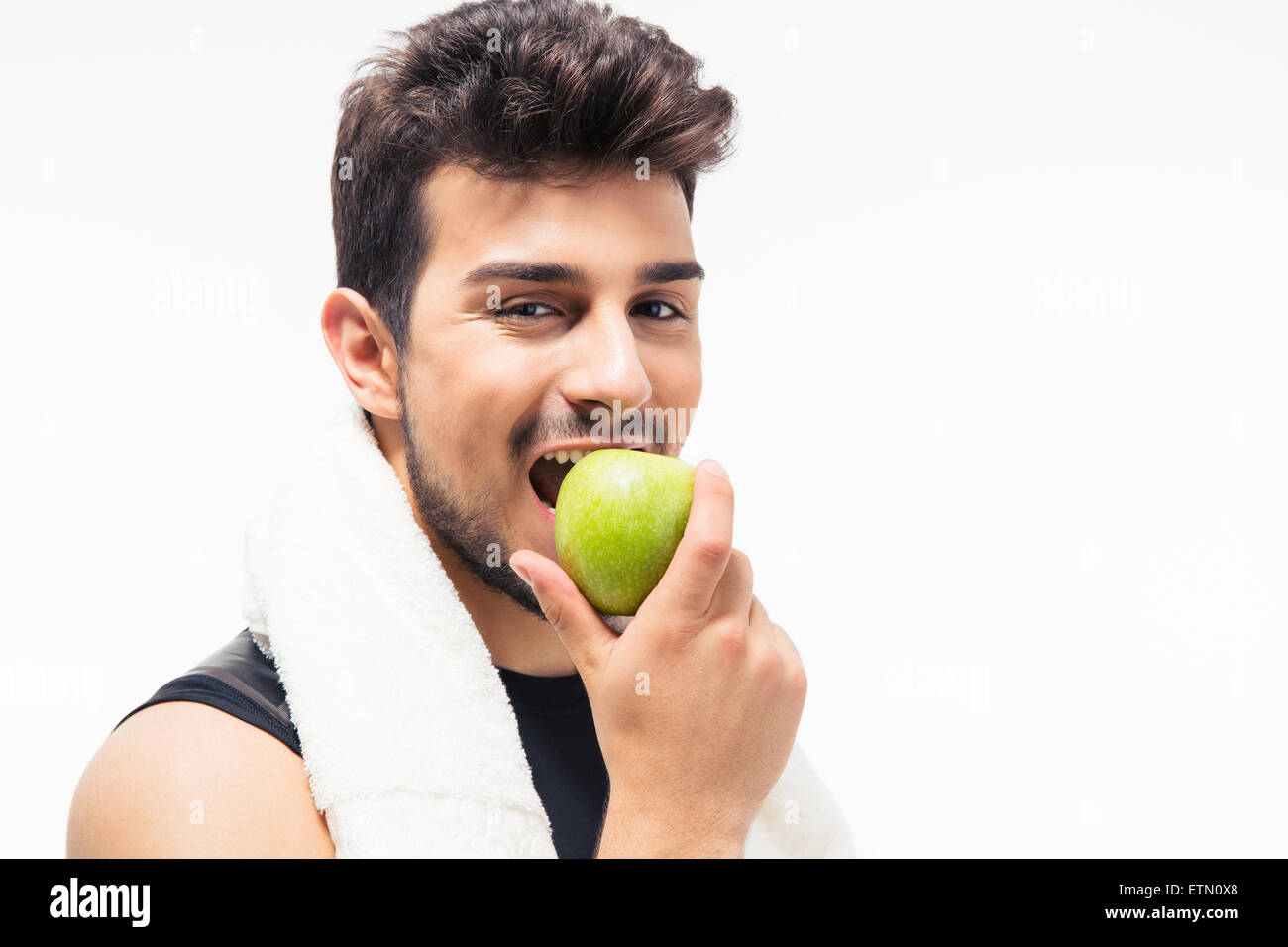 Sports man eating apple and looking at camera isolated on a white ...