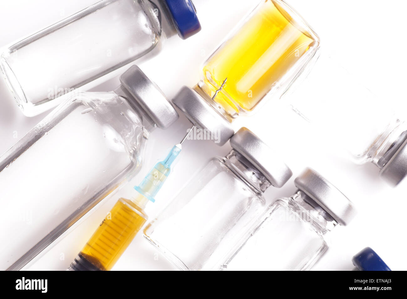 Vials with liquid and syringe filled with yellow substance Stock Photo ...