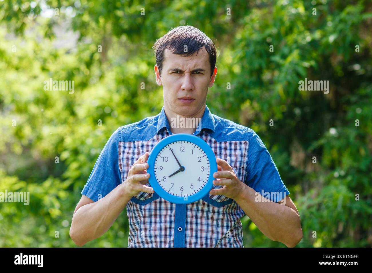 man holding a clock with both hands on a green background Summ Stock ...