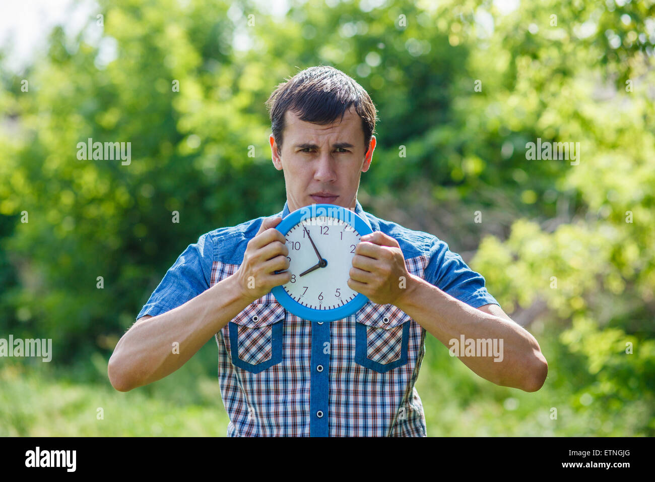 man holding a clock with both hands on a green background Summer Stock ...
