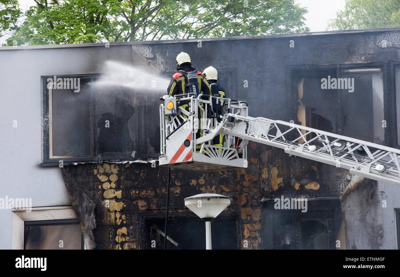 Firefighters are busy to extinguish a fire in a house on a lifting ramp ...