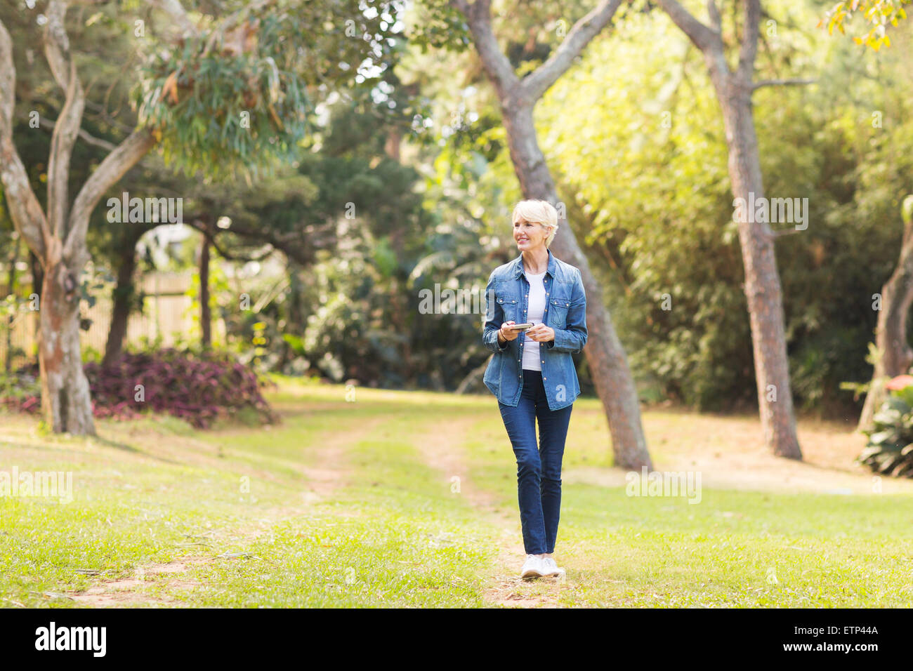 relaxed middle aged woman walking at the park Stock Photo - Alamy