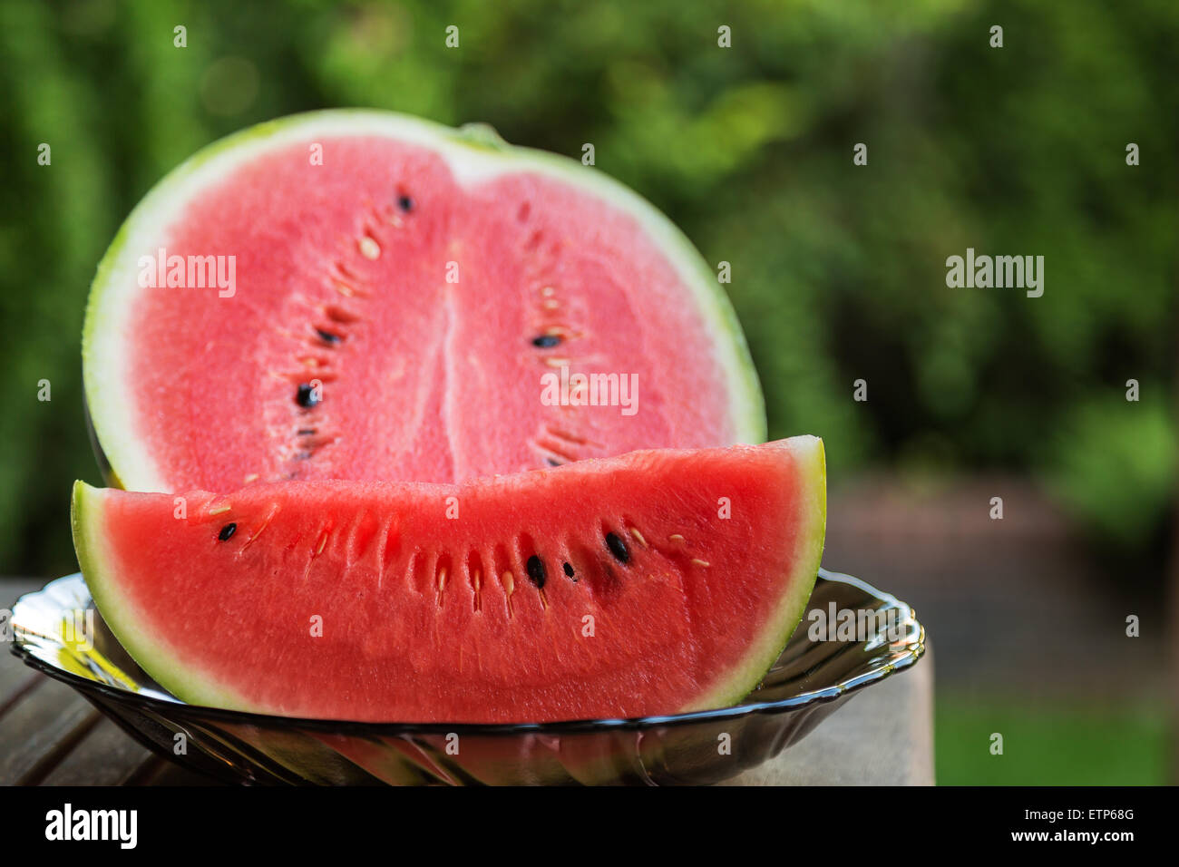 Half and one slice of watermelon on a woden table Stock Photo - Alamy