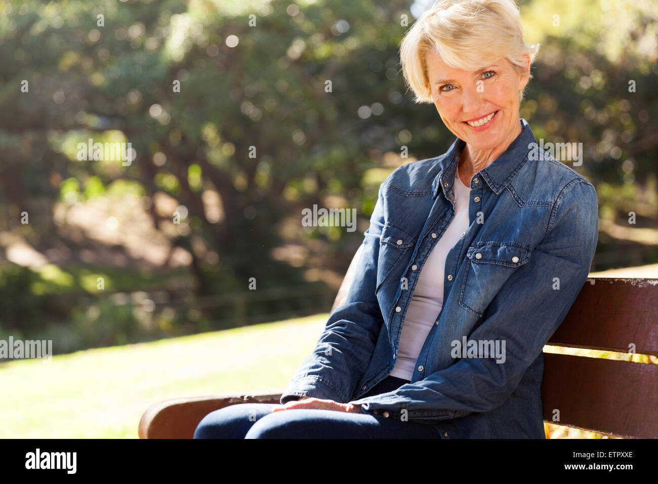 attractive senior woman sitting on a bench outdoors Stock Photo - Alamy