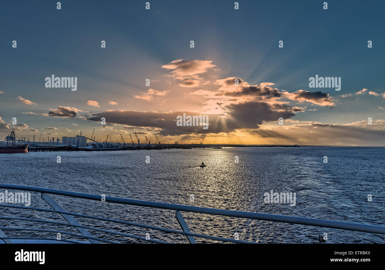 Sun setting behind a large cloud radiating sun rays over the River ...