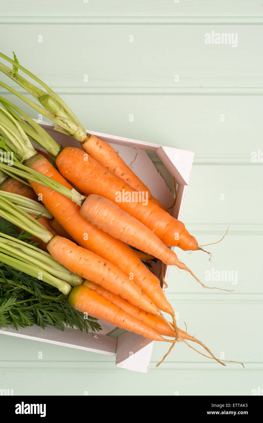 Carrots inside white wooden box on the light green wooden table Stock ...