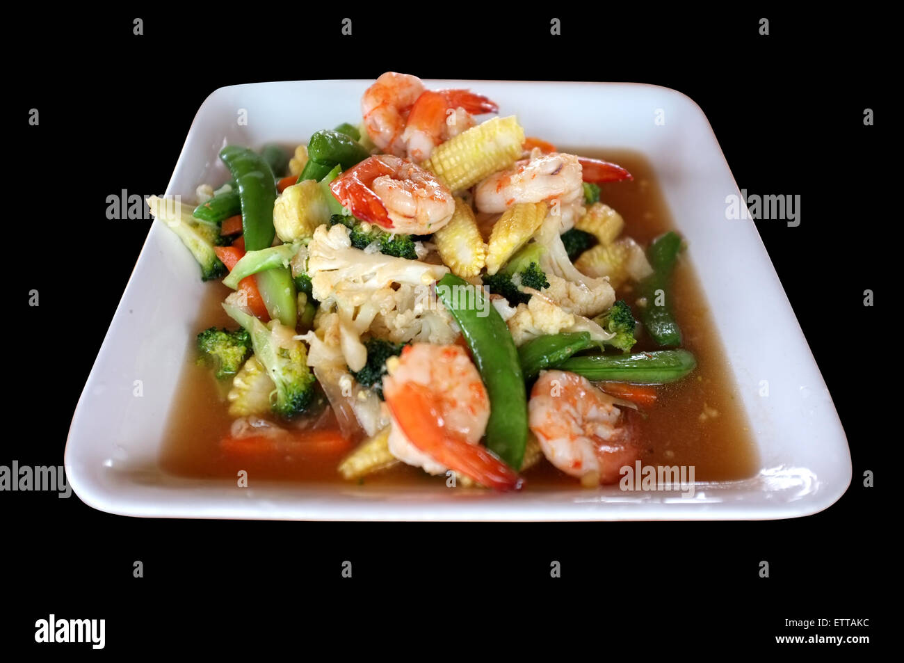 Stir fry mixed vegetables and shrimp in white dish isolated on black ...