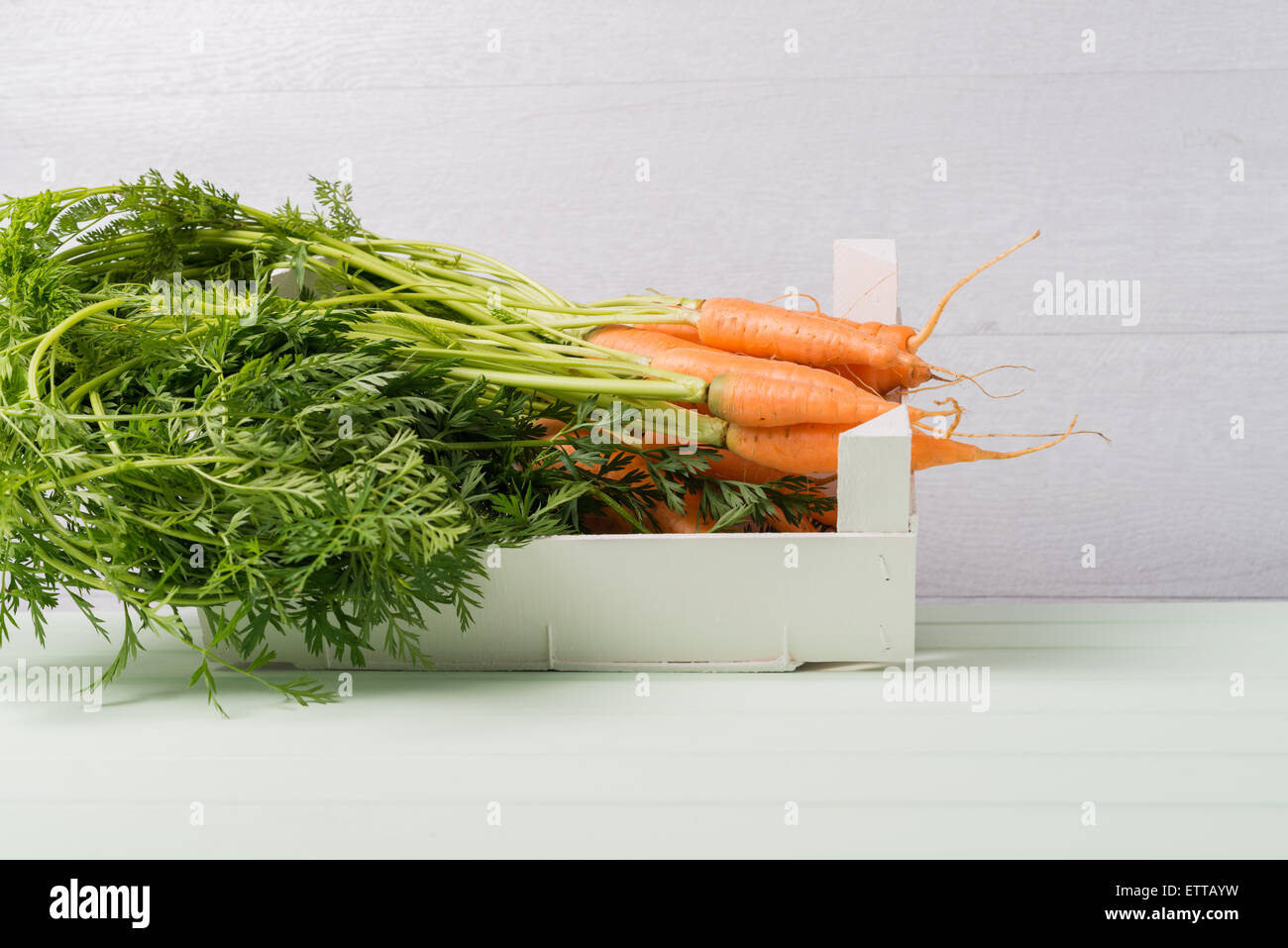Carrots inside white wooden box on the light green wooden table Stock ...
