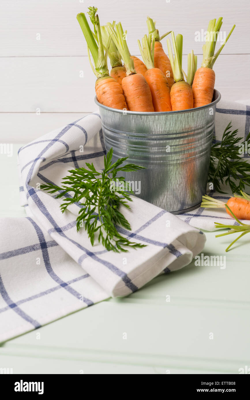 Carrots inside a metal bucket on the light green wooden table Stock ...