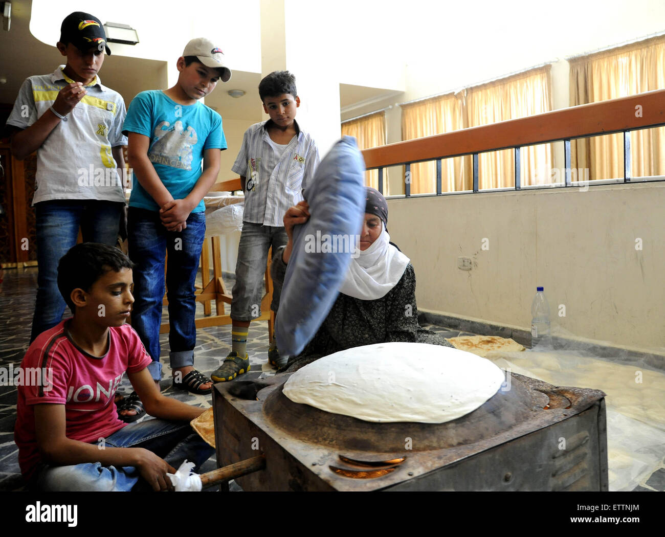 Damascus, Syria. 15th June, 2015. Syrian kids watch how to make bread ...
