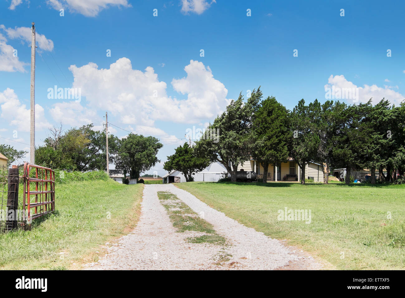 A long gravel driveway leading to a farm house and outbuildings in ...