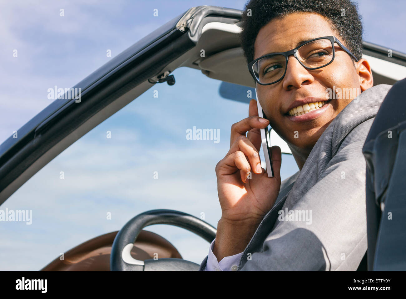 Young black man sitting in convertible, talking on the phone Stock ...