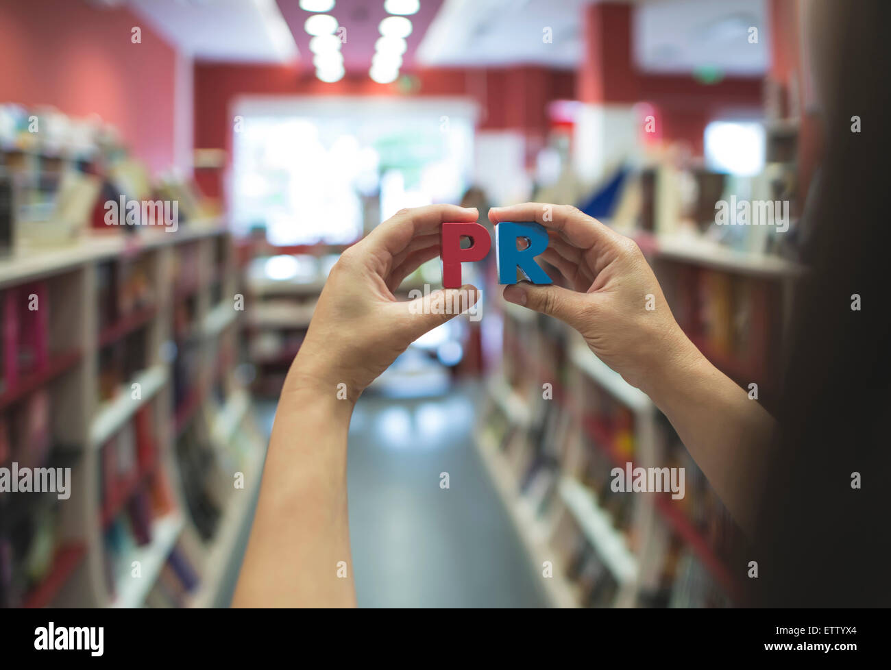 Hands holding letters PR in a bookstore Stock Photo - Alamy