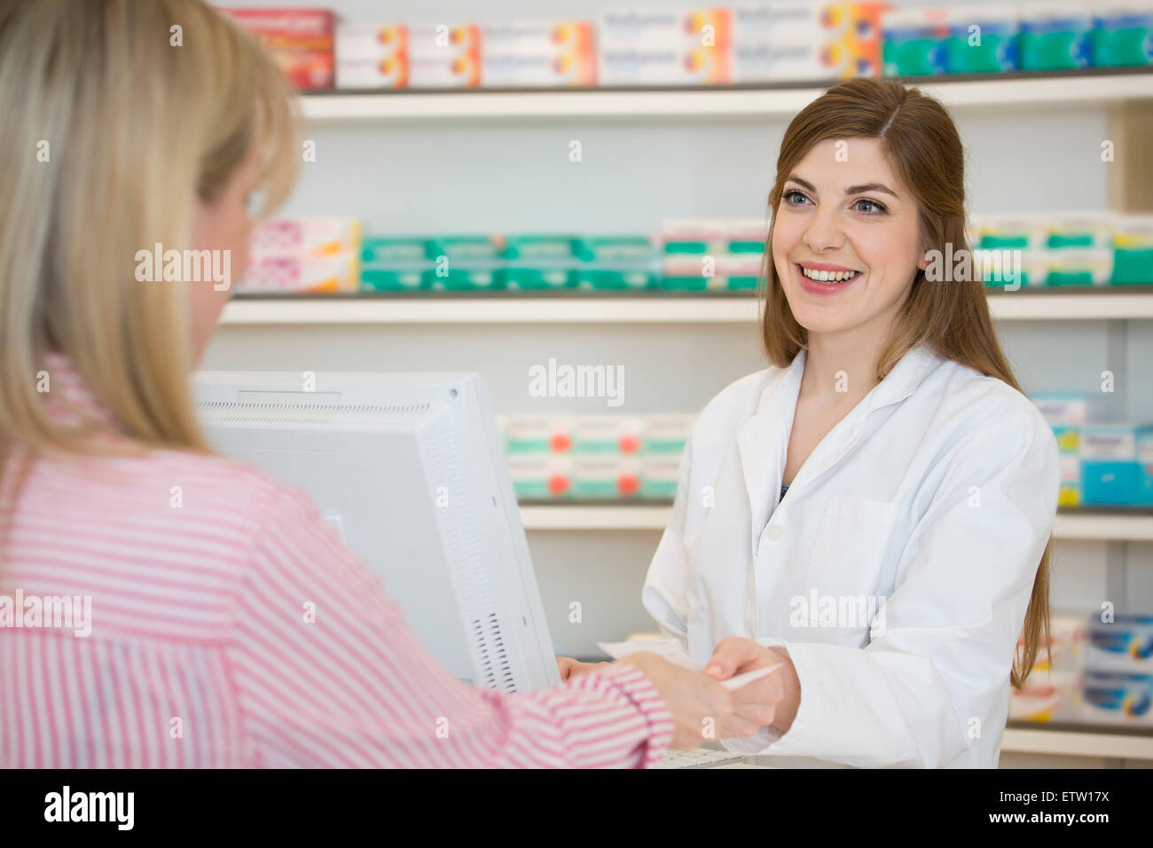 Portrait of smiling female pharmacist taking prescription from customer ...
