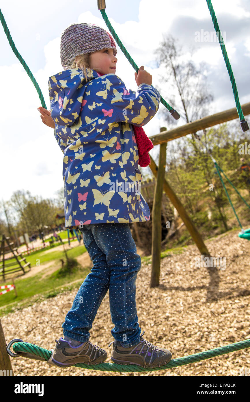 Little girl balancing on a rope on playground Stock Photo - Alamy