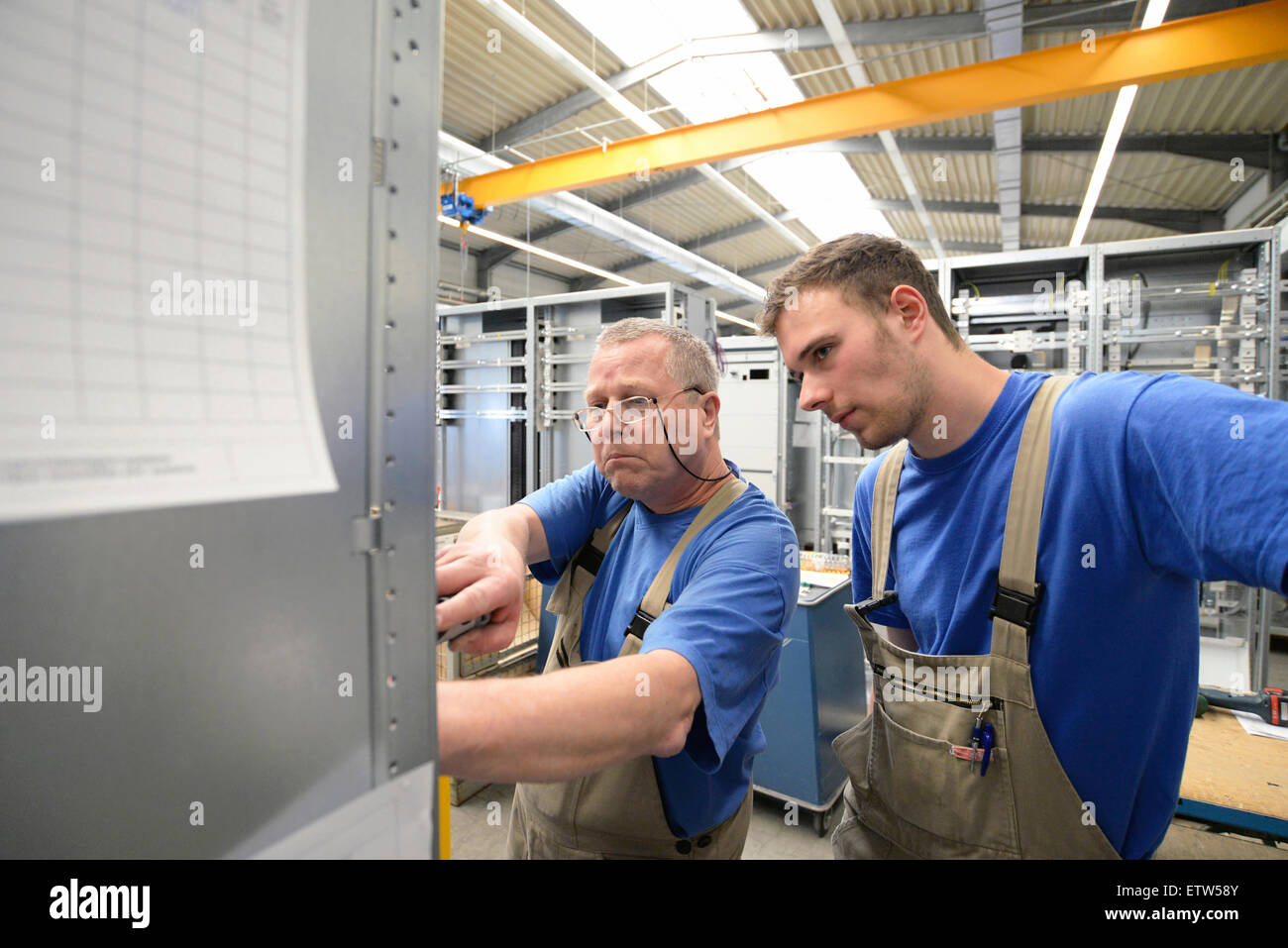 Two workers in a switchboard construction factory Stock Photo - Alamy
