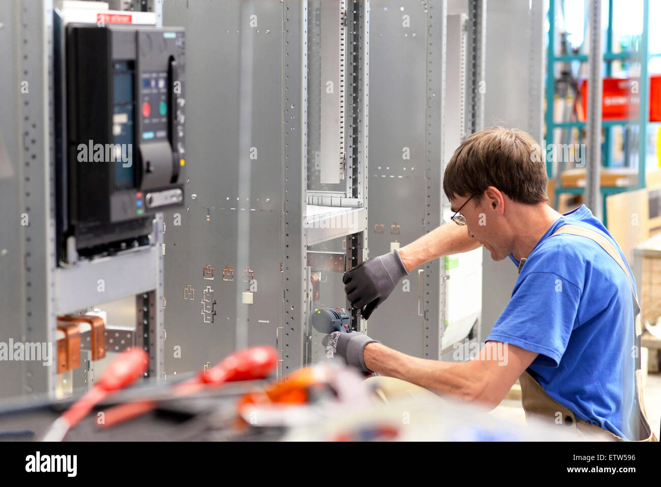 Worker in a switchboard construction factory Stock Photo - Alamy