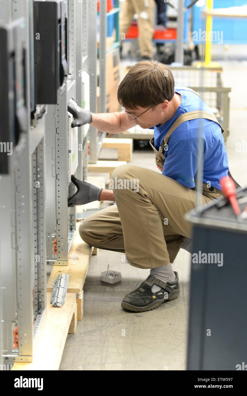 Worker in a switchboard construction factory Stock Photo - Alamy