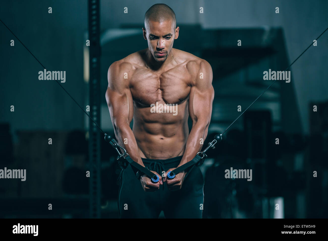 Young man training pectoral muscles at cable crossover in gym Stock ...