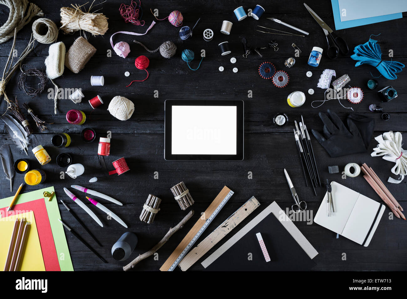 Arrangement of craft materials, tools and digital tablet on black wood ...