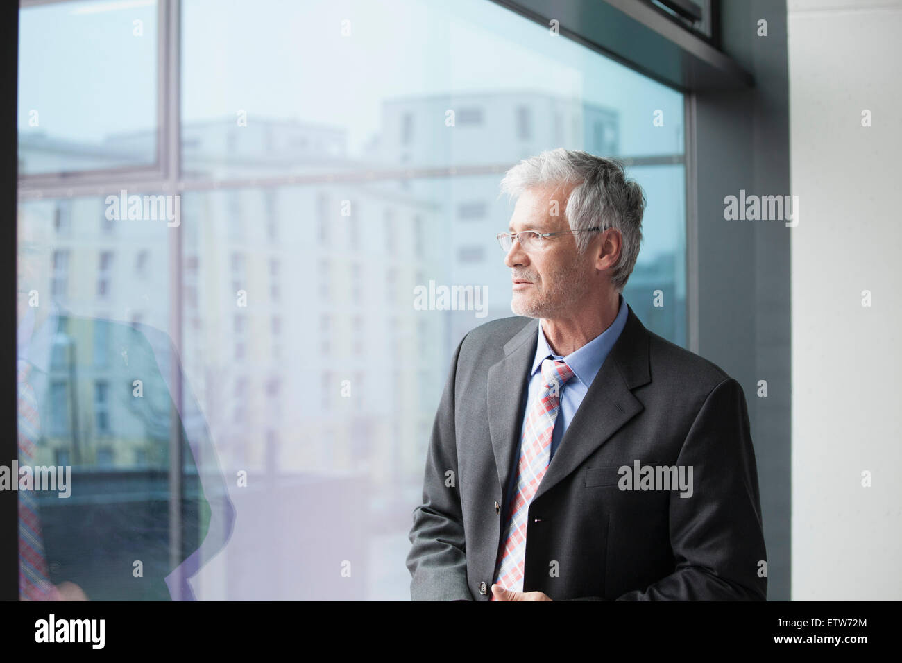 Businessman standing window looking distance hi-res stock photography ...
