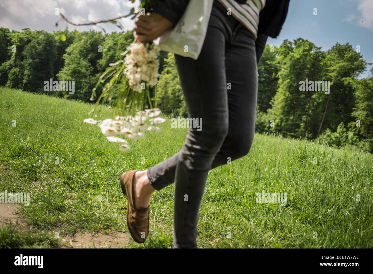 Woman walking with flowers on meadow Stock Photo - Alamy