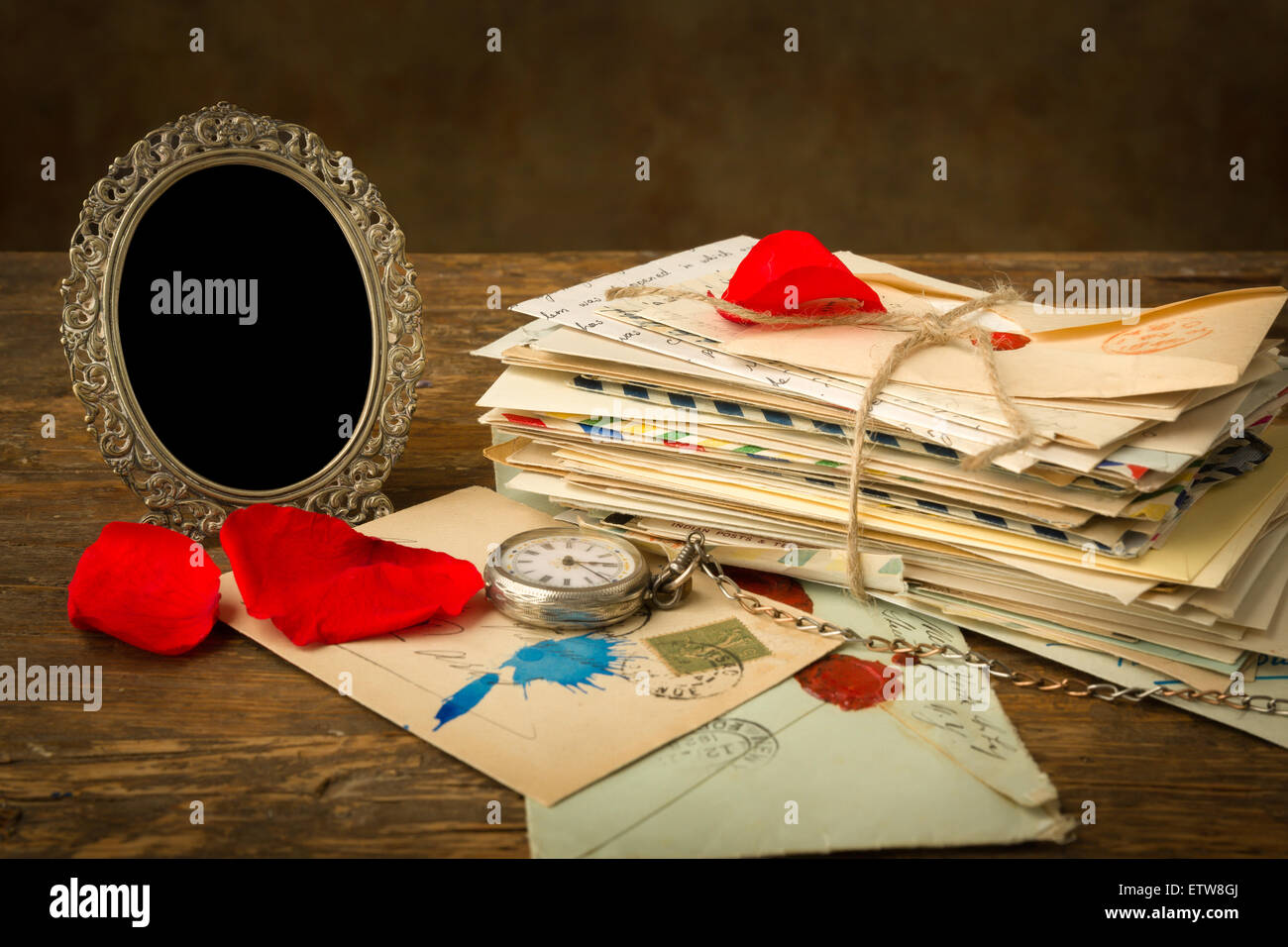 Empty antique picture frame and a pile of old letters on a wooden table ...
