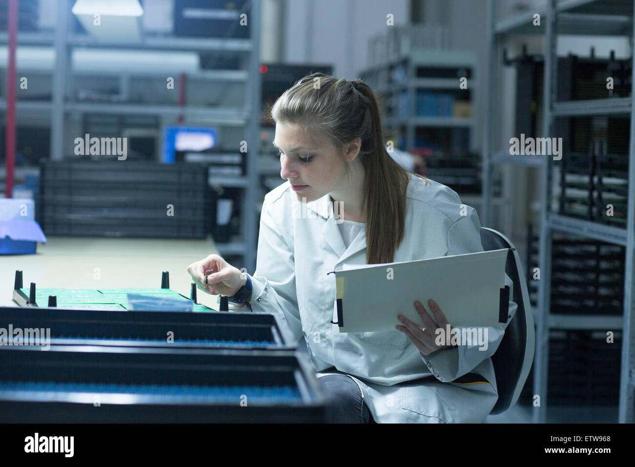 Technician holding clipboard working on circuit board Stock Photo - Alamy