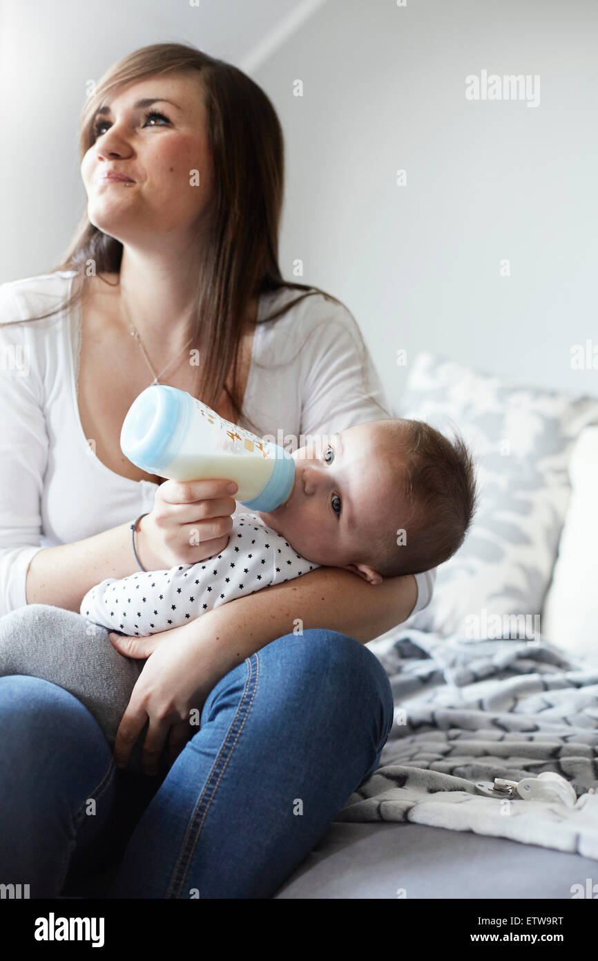 Young mother bottle-feeding baby at home Stock Photo - Alamy
