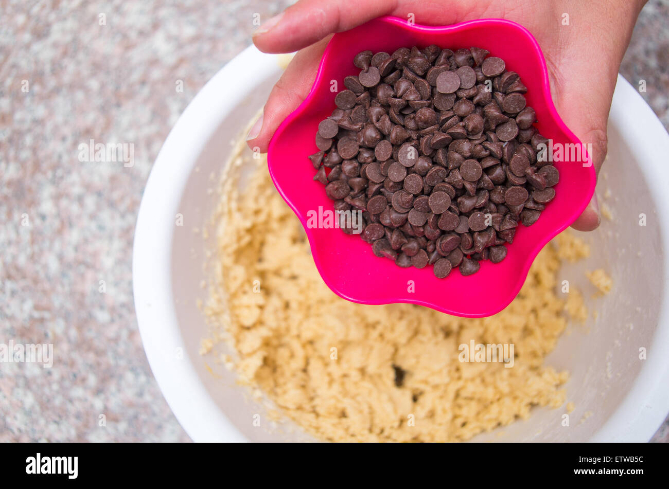 Pouring chocolate chip pieces into yellow cookie dough Stock Photo - Alamy