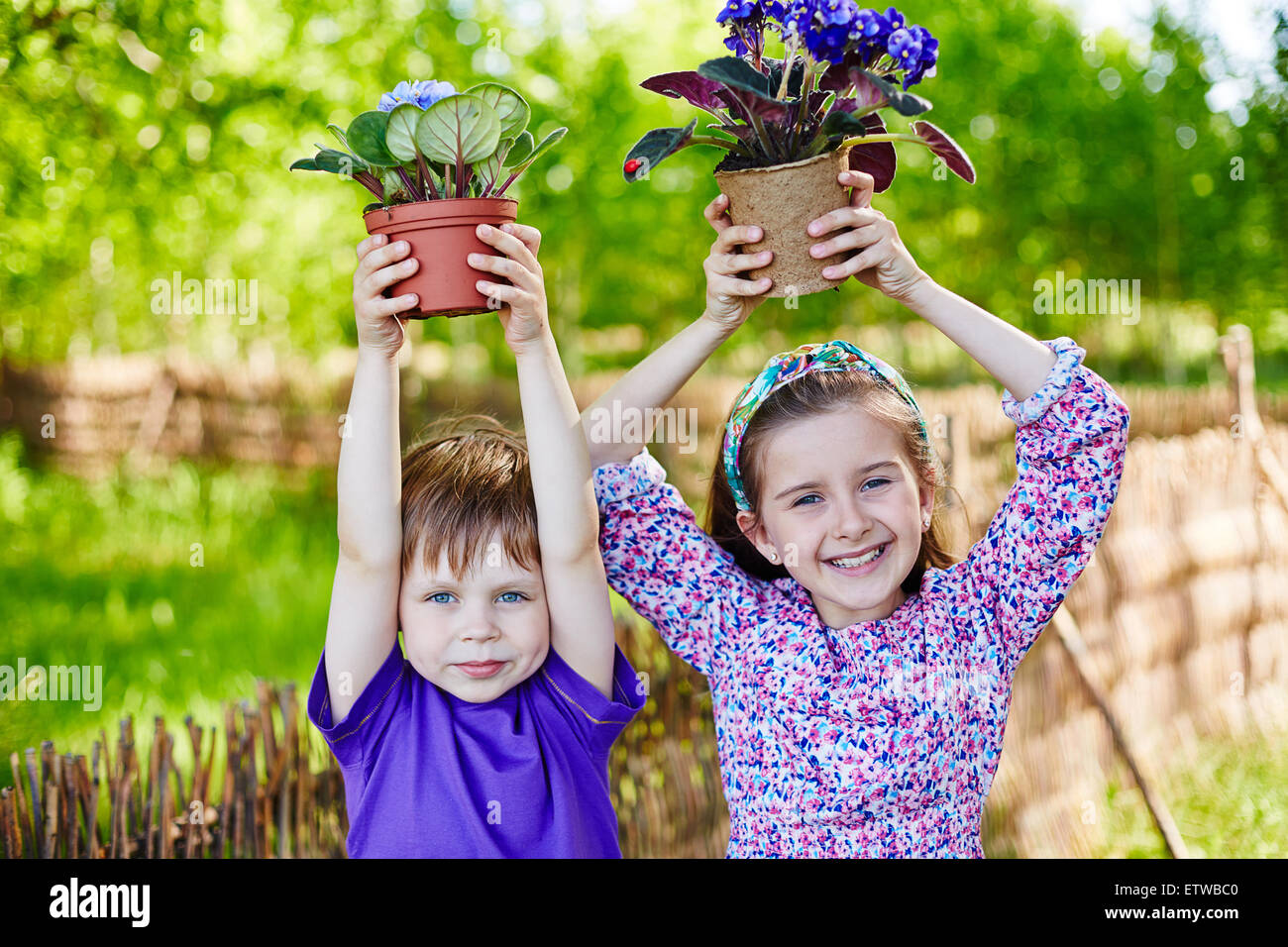 Happy kids with newly planted violets looking at camera in natural ...