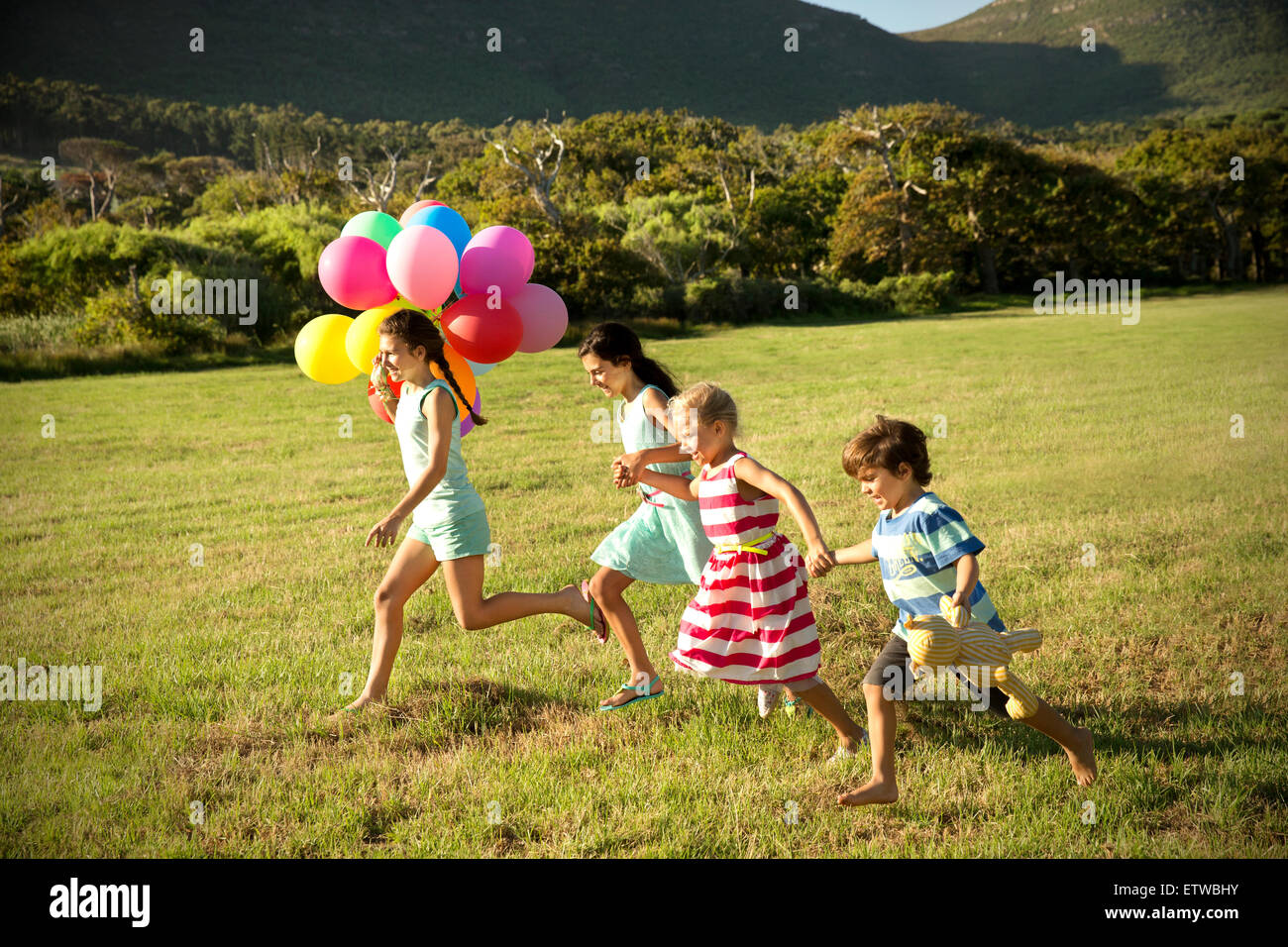 Happy children running with balloons on meadow Stock Photo - Alamy
