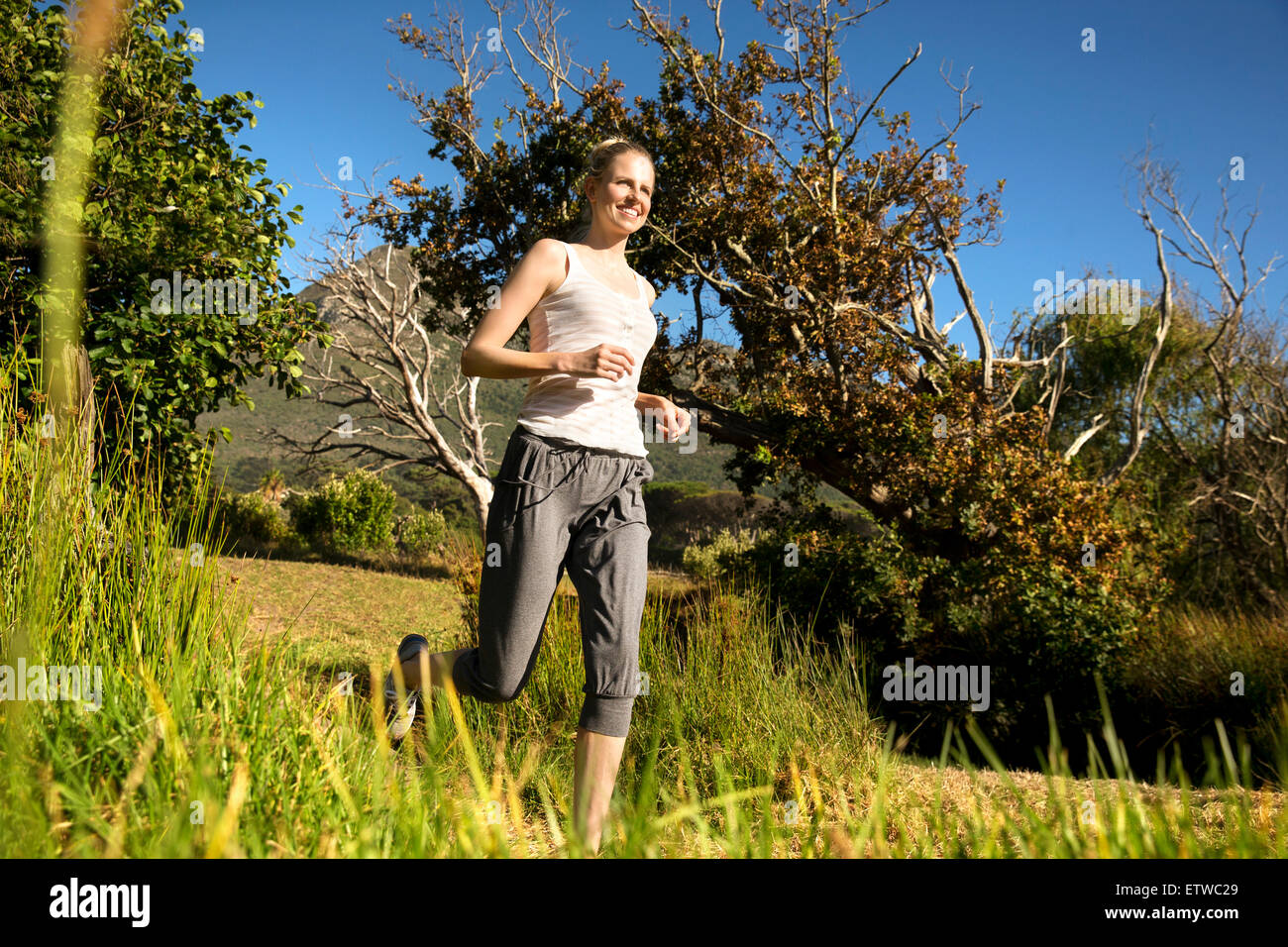 Smiling woman jogging in rural landscape Stock Photo - Alamy