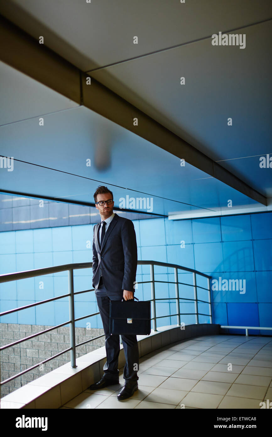 Young agent with briefcase standing by railings Stock Photo - Alamy