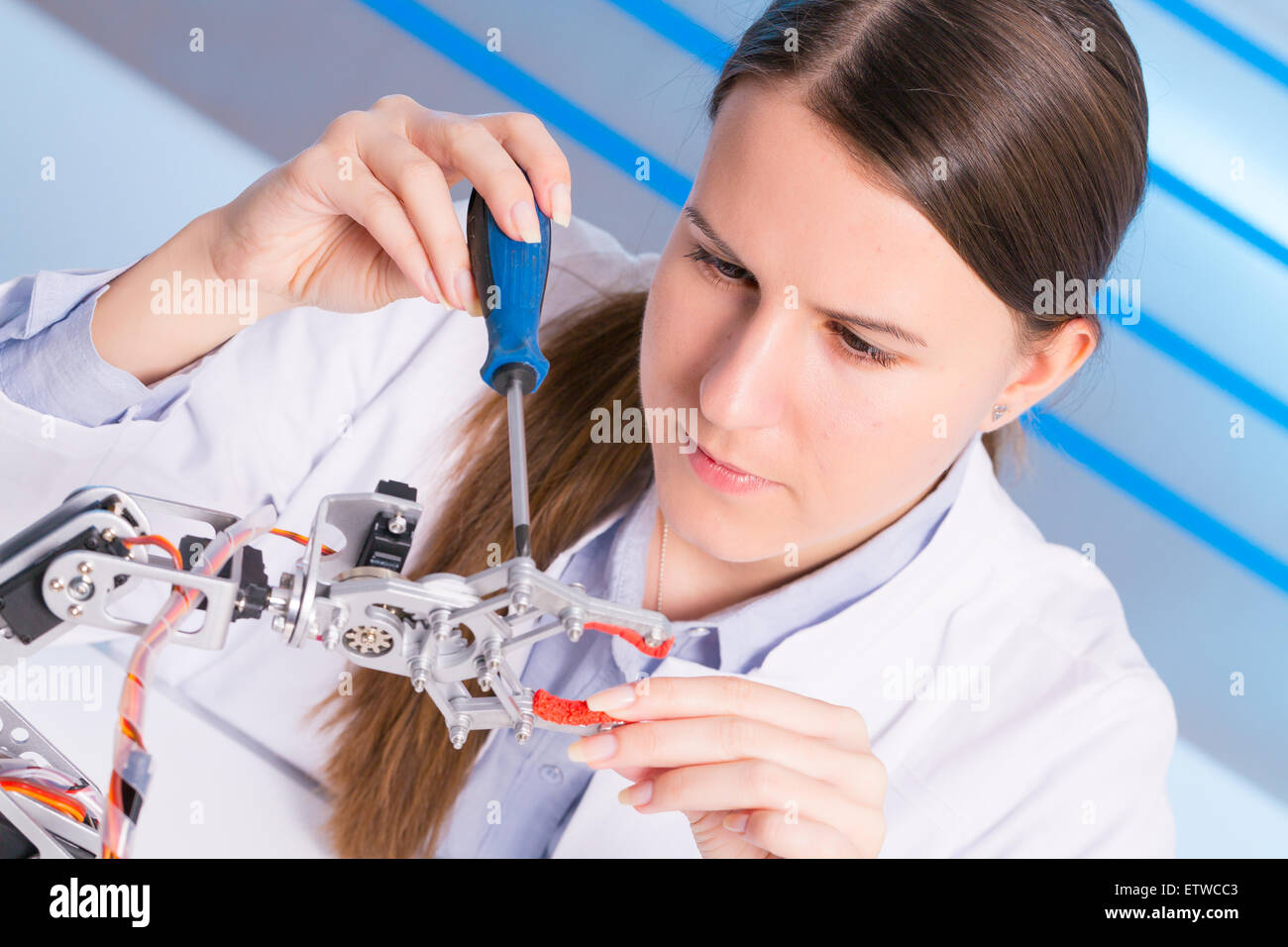 schoolgirl adjusts the robot arm model, girl in a robotics laboratory ...