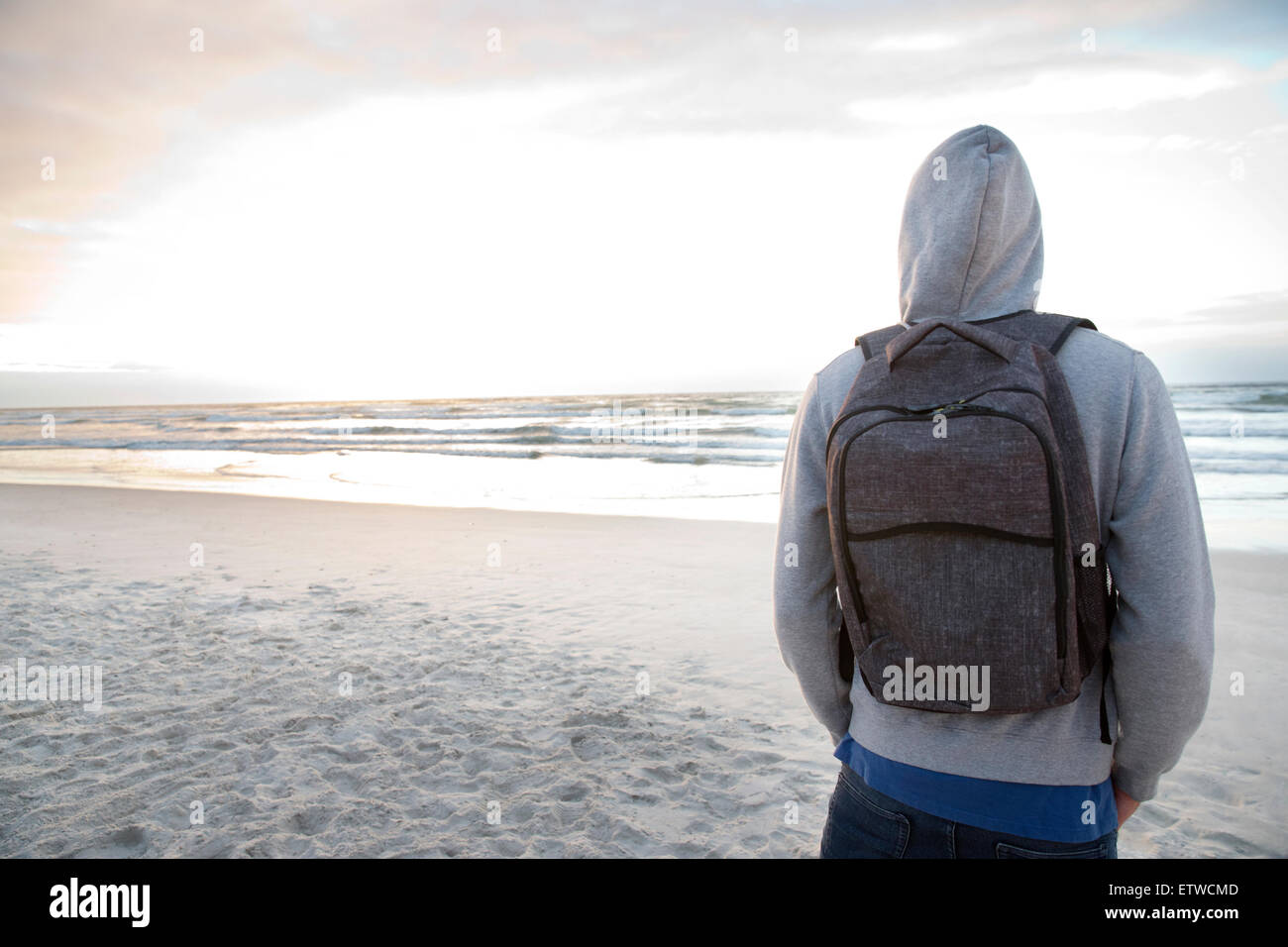 Young man with backpack on beach at sunrise Stock Photo - Alamy