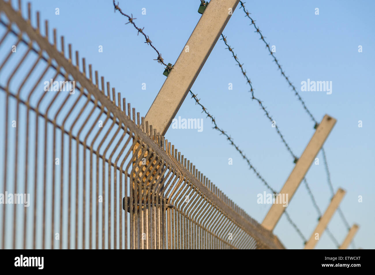 Security post with barbed wire fence closeup Stock Photo - Alamy