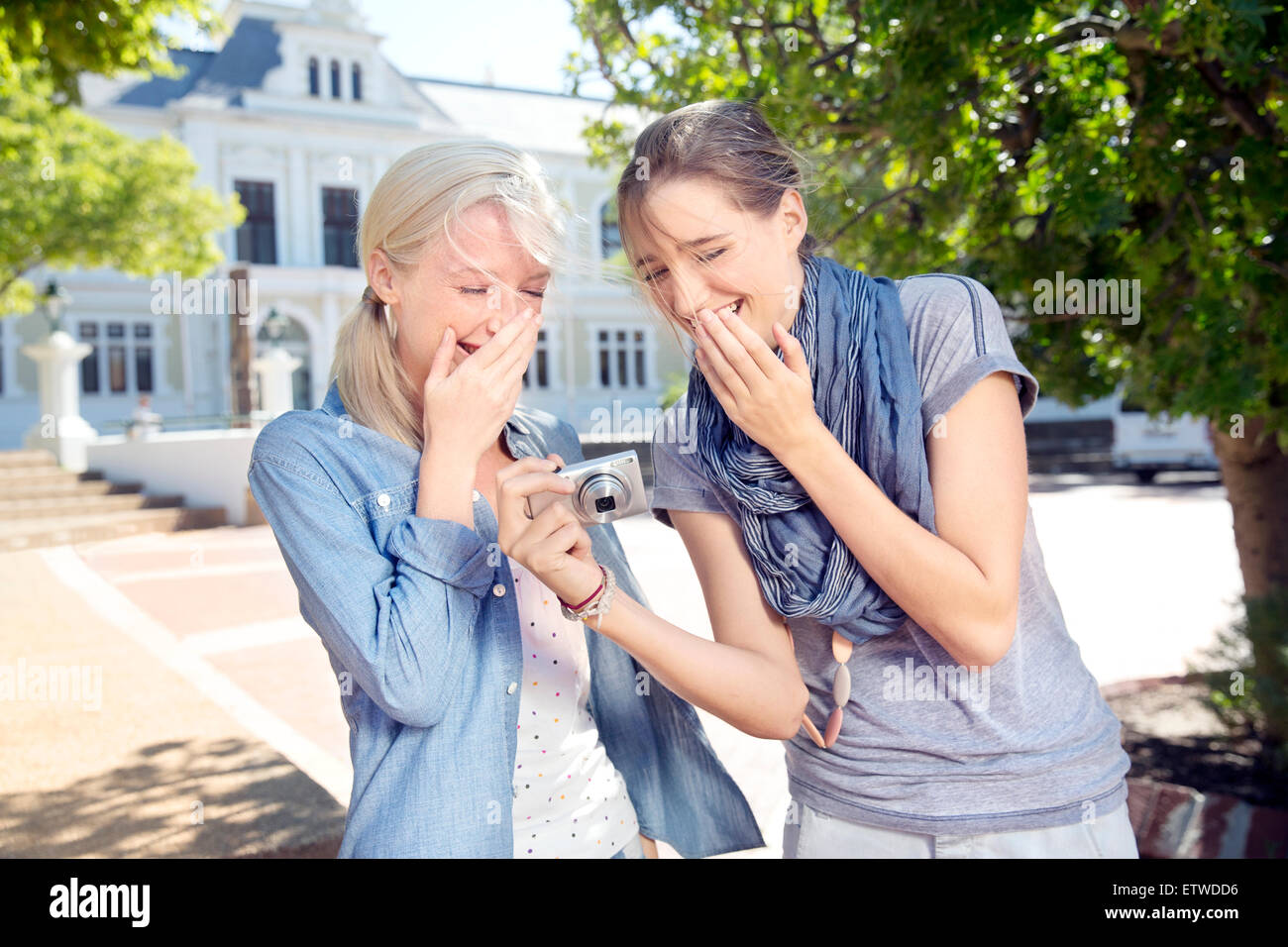 Two laughing young women outdoors looking at camera Stock Photo - Alamy