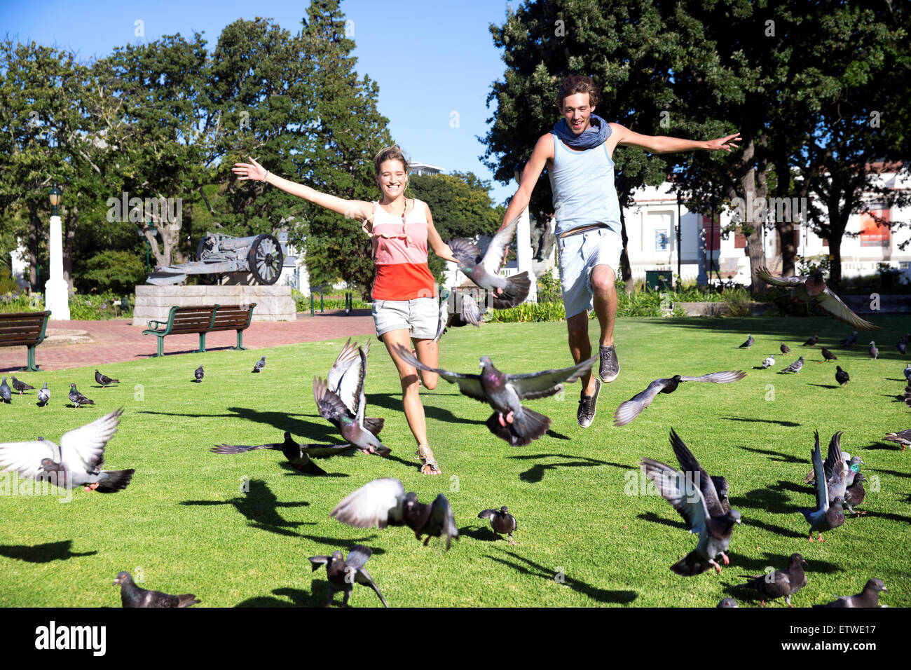 Enthusiastic young couple chasing pigeons in park Stock Photo - Alamy