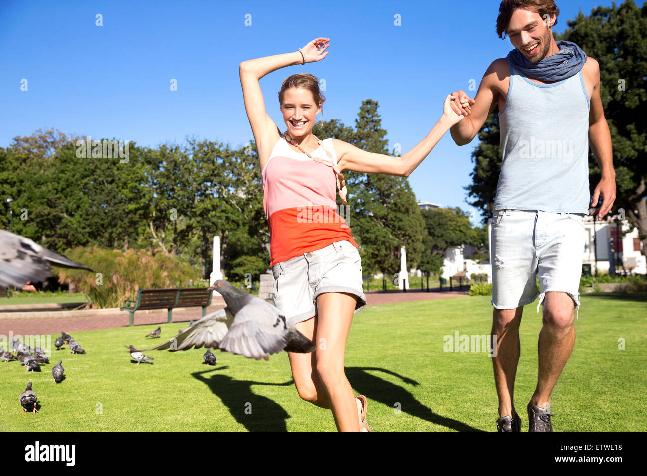 Enthusiastic young couple chasing pigeons in park Stock Photo - Alamy
