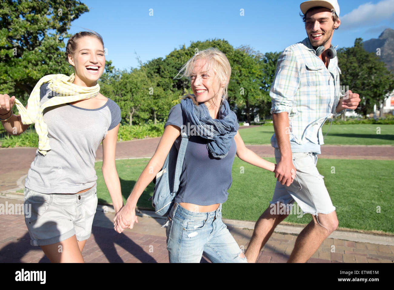 Enthusiastic friends running hand in hand Stock Photo - Alamy