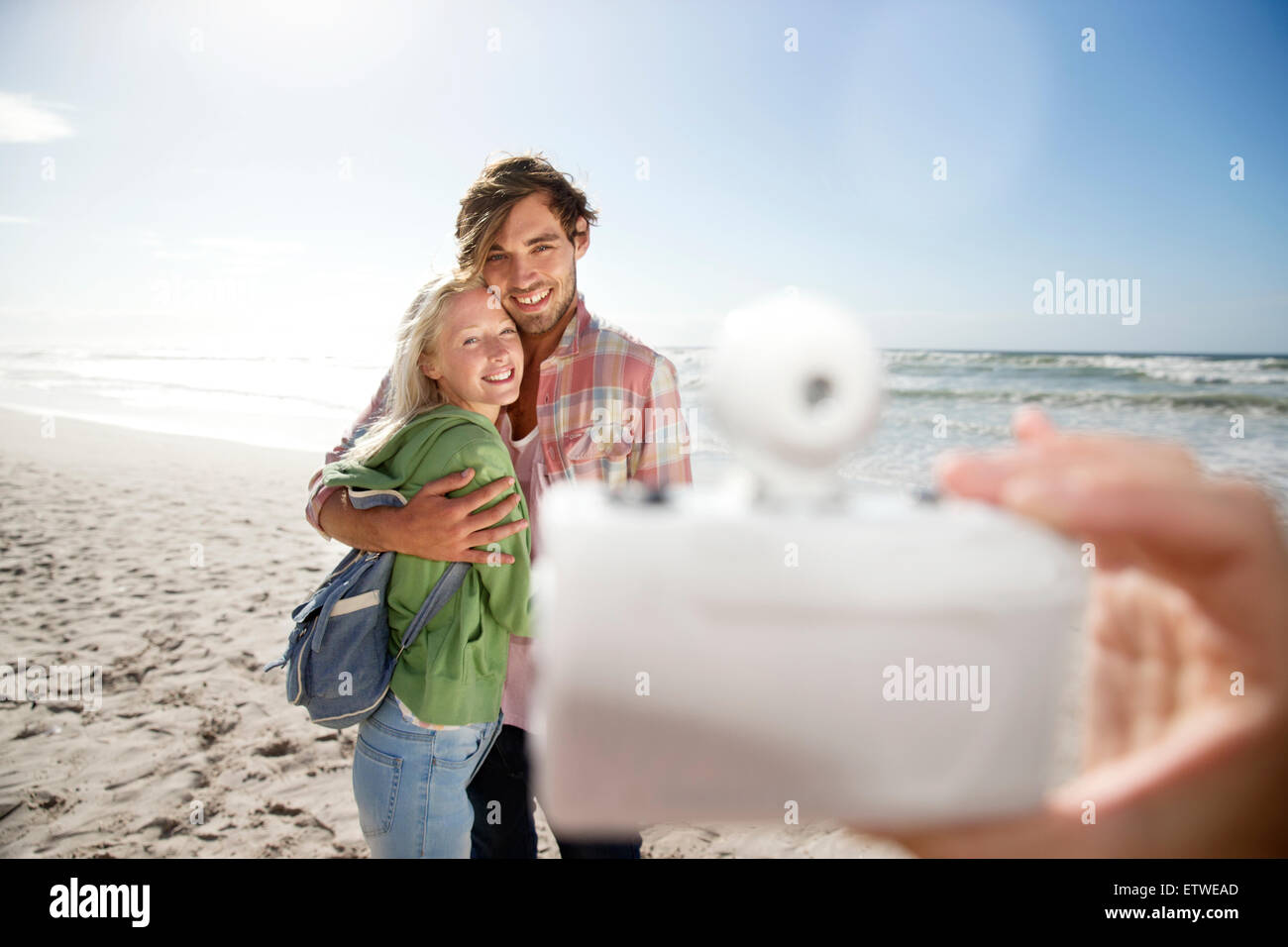 Happy young couple on beach being photographed Stock Photo - Alamy