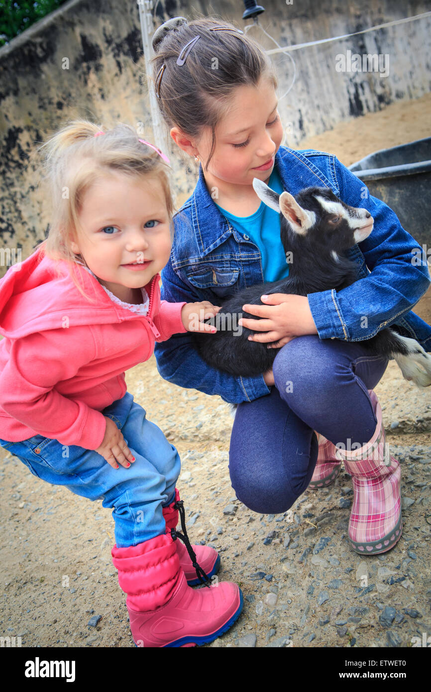 little girls with a goat kid in front of the farm Stock Photo - Alamy