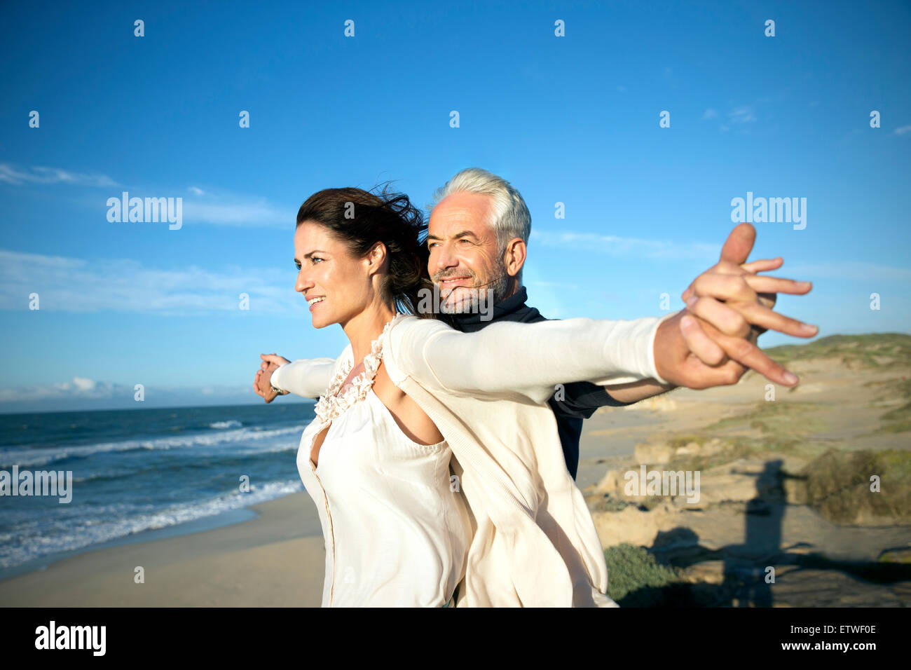 South Africa, couple with outstretched arms standing on the beach ...